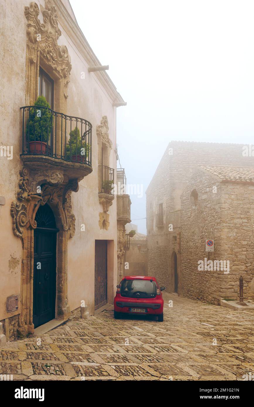 Stone square in Erice with a red car Stock Photo - Alamy