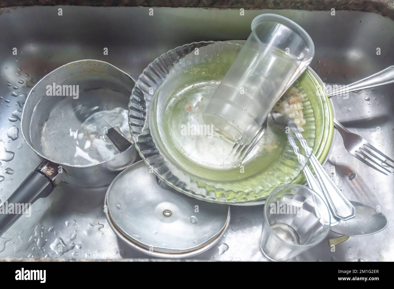 Dirty dishes, dishes, cutlery and dirty pots in a simple home sink,real ...