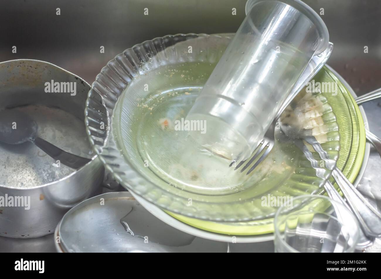 Dirty dishes, dishes, cutlery and dirty pots in a simple home sink,real ...
