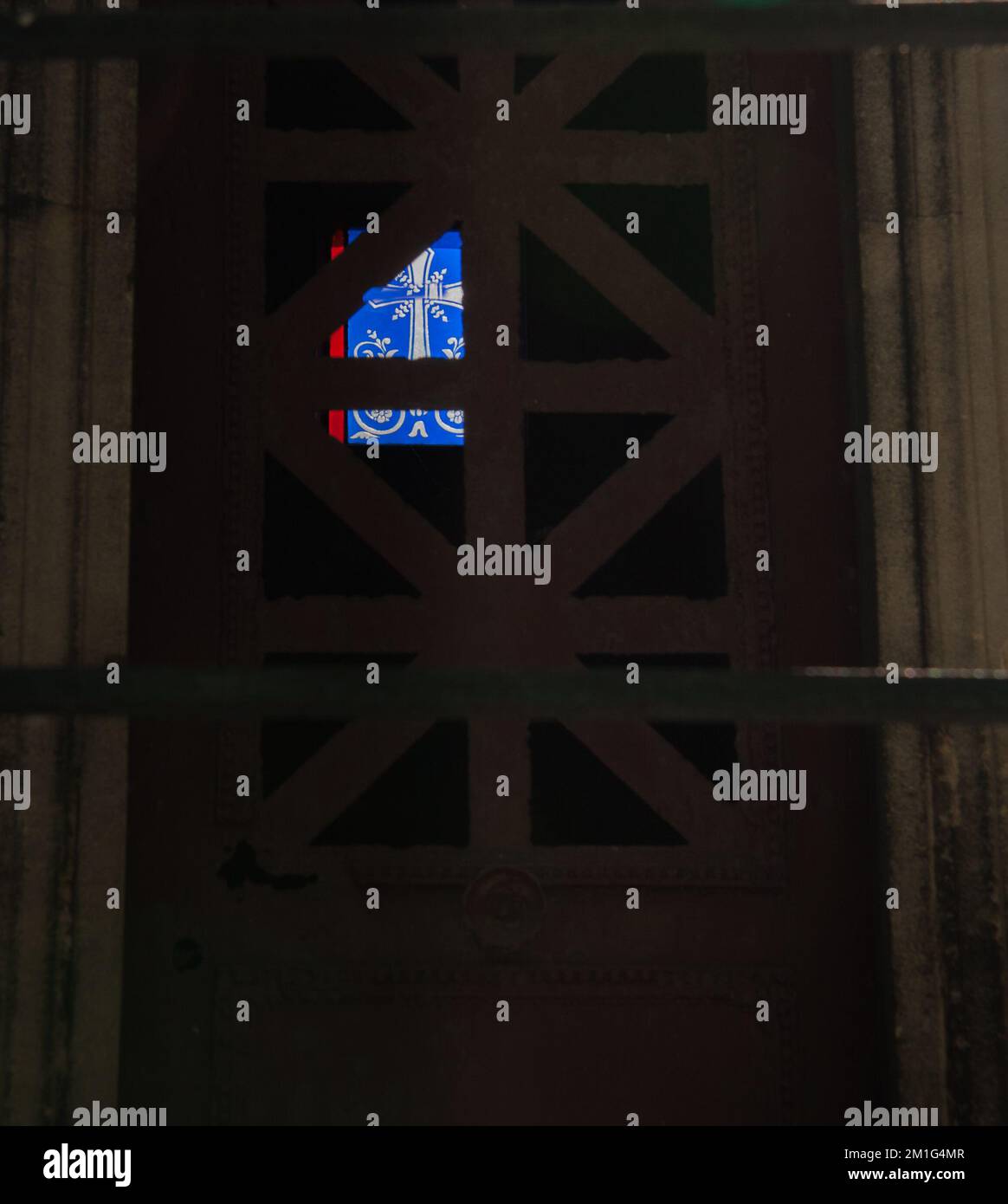 Stained glass window seen through a neglected and rusting entrance of a ...