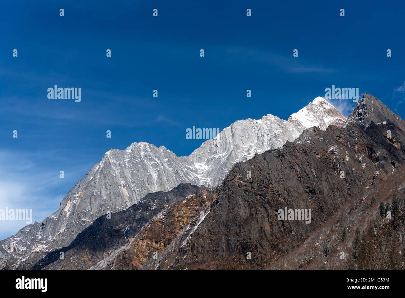 A scenic view of Mount Siguniang slopes under the clear blue sky ...