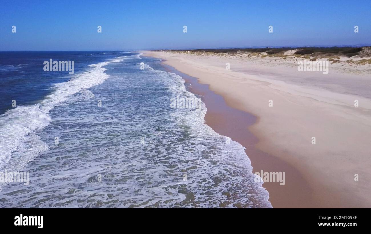 Low flying along over white waves rolling in and out on sand beach ...