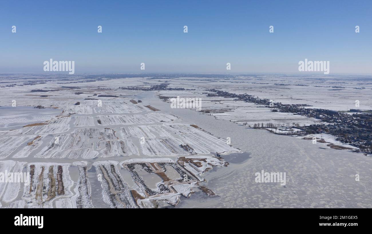 An aerial shot of frozen snowy white fields near a city with a skyline ...