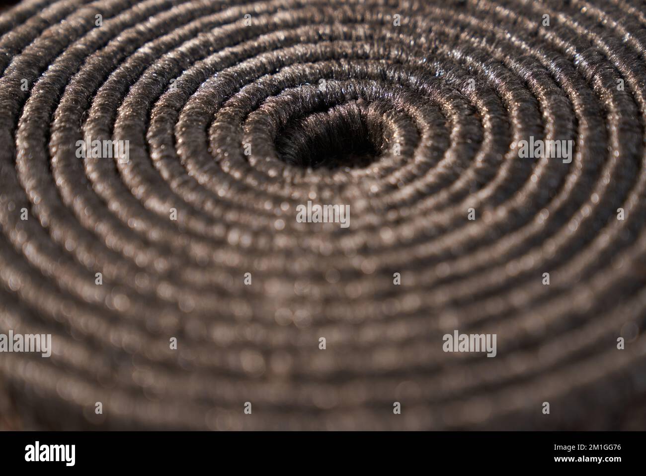 Textured backdrop of rolled up grey carpet edge, with small void in ...