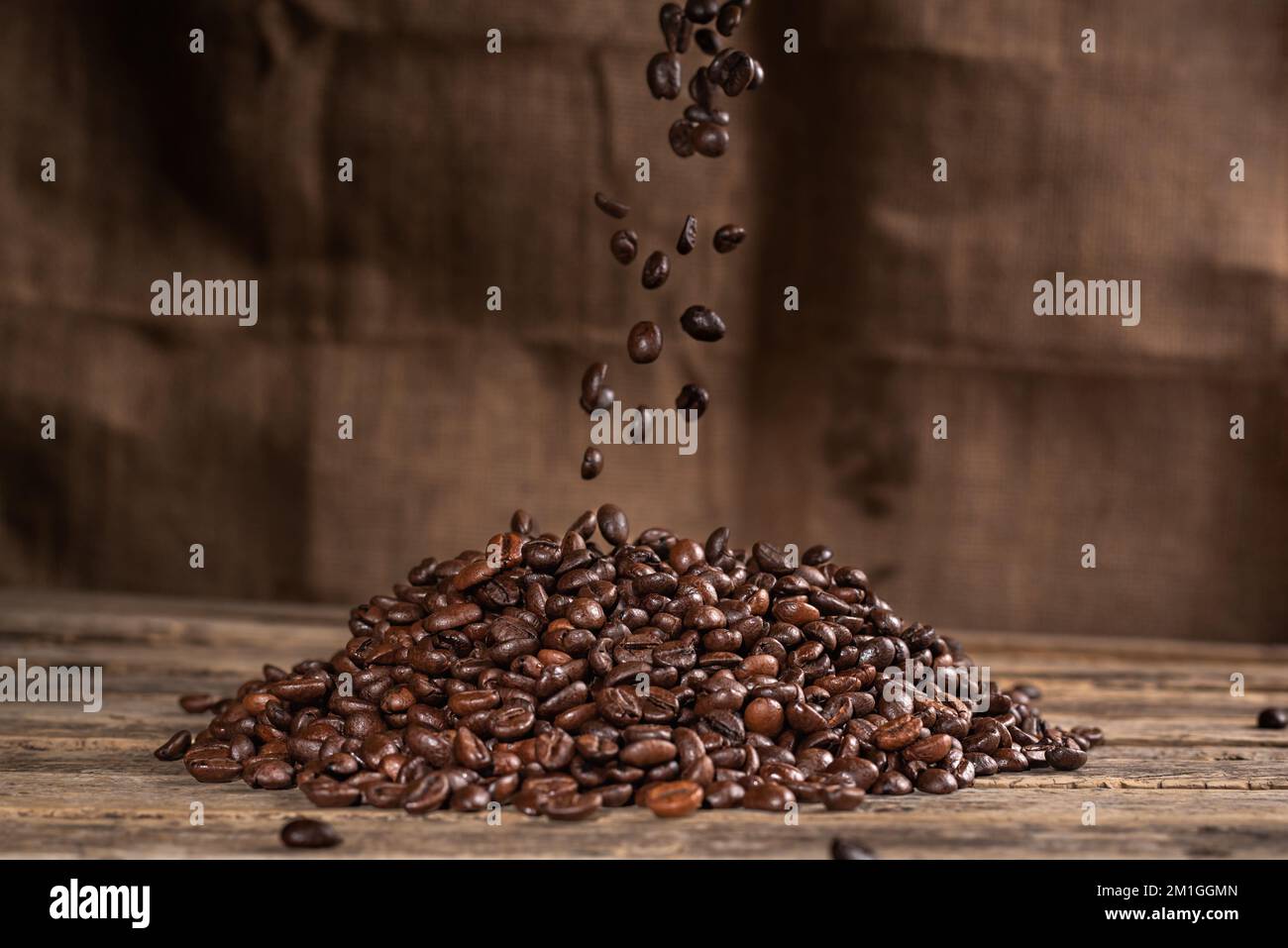 Coffee beans falling on an old wooden table and creating a small pile ...