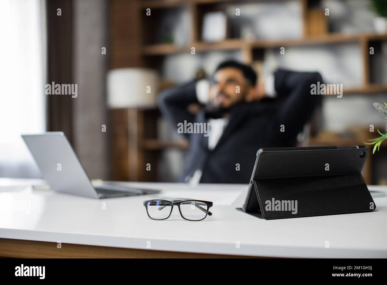 Focus on eye glasses, tablet and laptop. Happy relaxed caucasian young ...