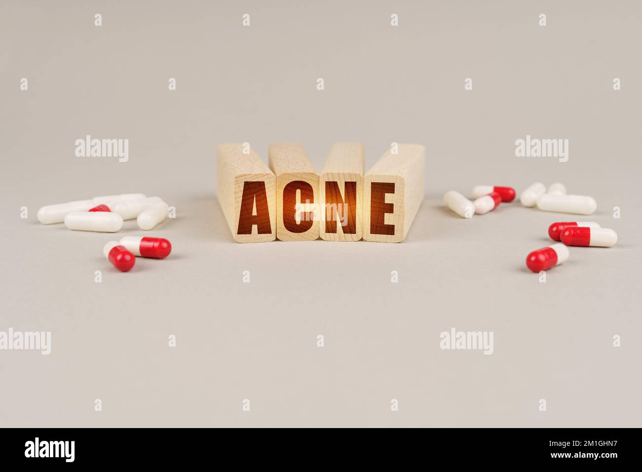 Medical concept. On a gray surface are pills and a red wooden block ...