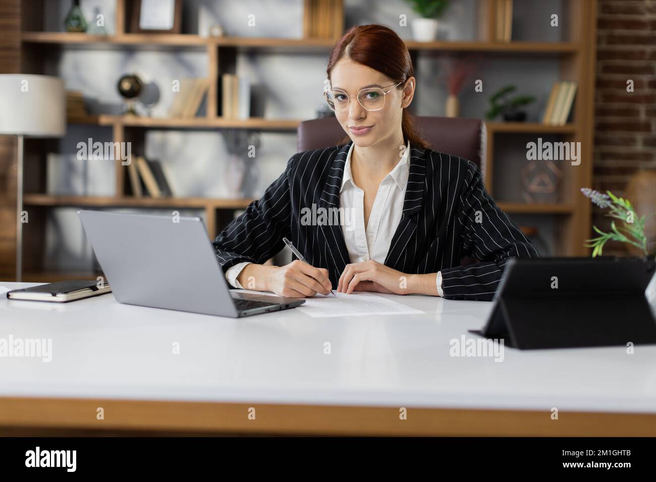 Young pretty female accountant working from modern office using laptop ...