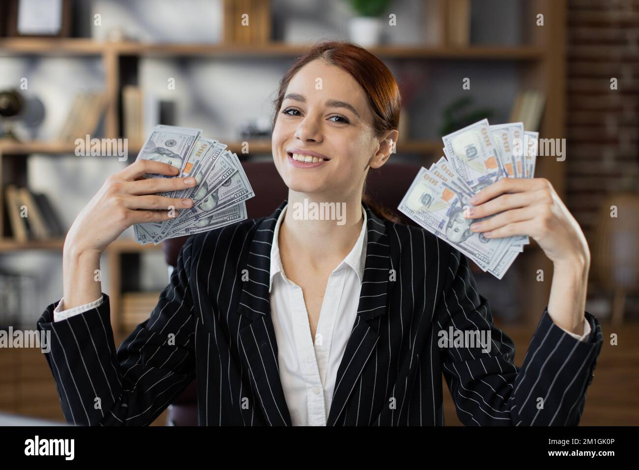 Portrait of happy young attractive female accountant holding cash ...