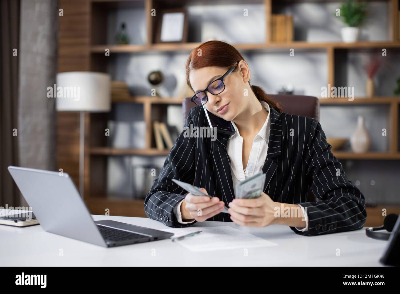 Rich business woman working on smartphone counting money cash ...