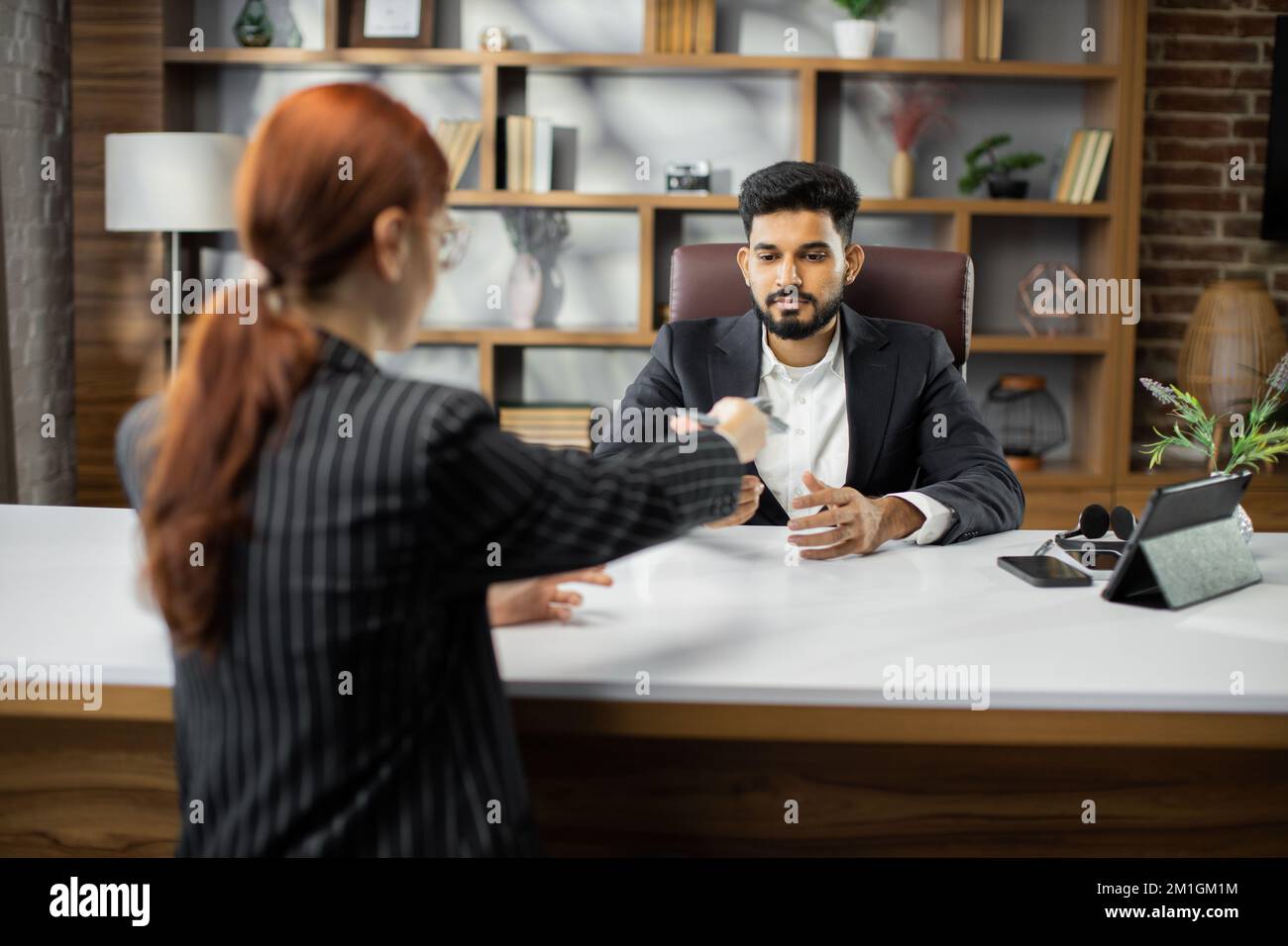 Back view of young red hair businesswoman giving bribe to smiling ...