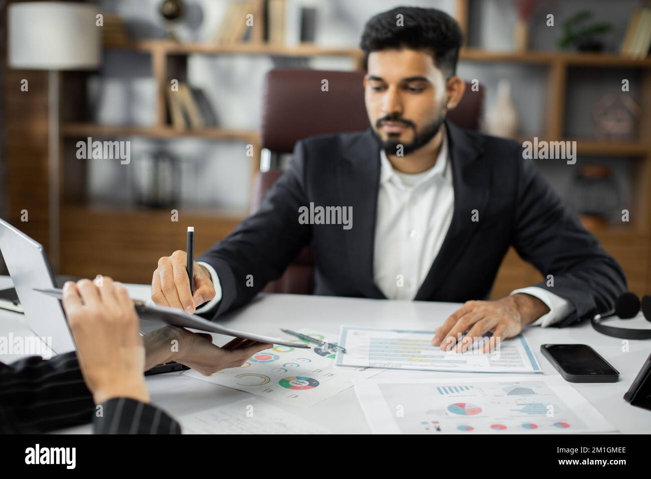 Focused young businessman signing agreement with skilled female lawyer ...