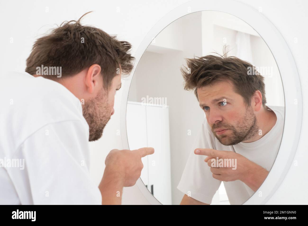 Man trying to encourage himself showing thumb up looking in mirror ...