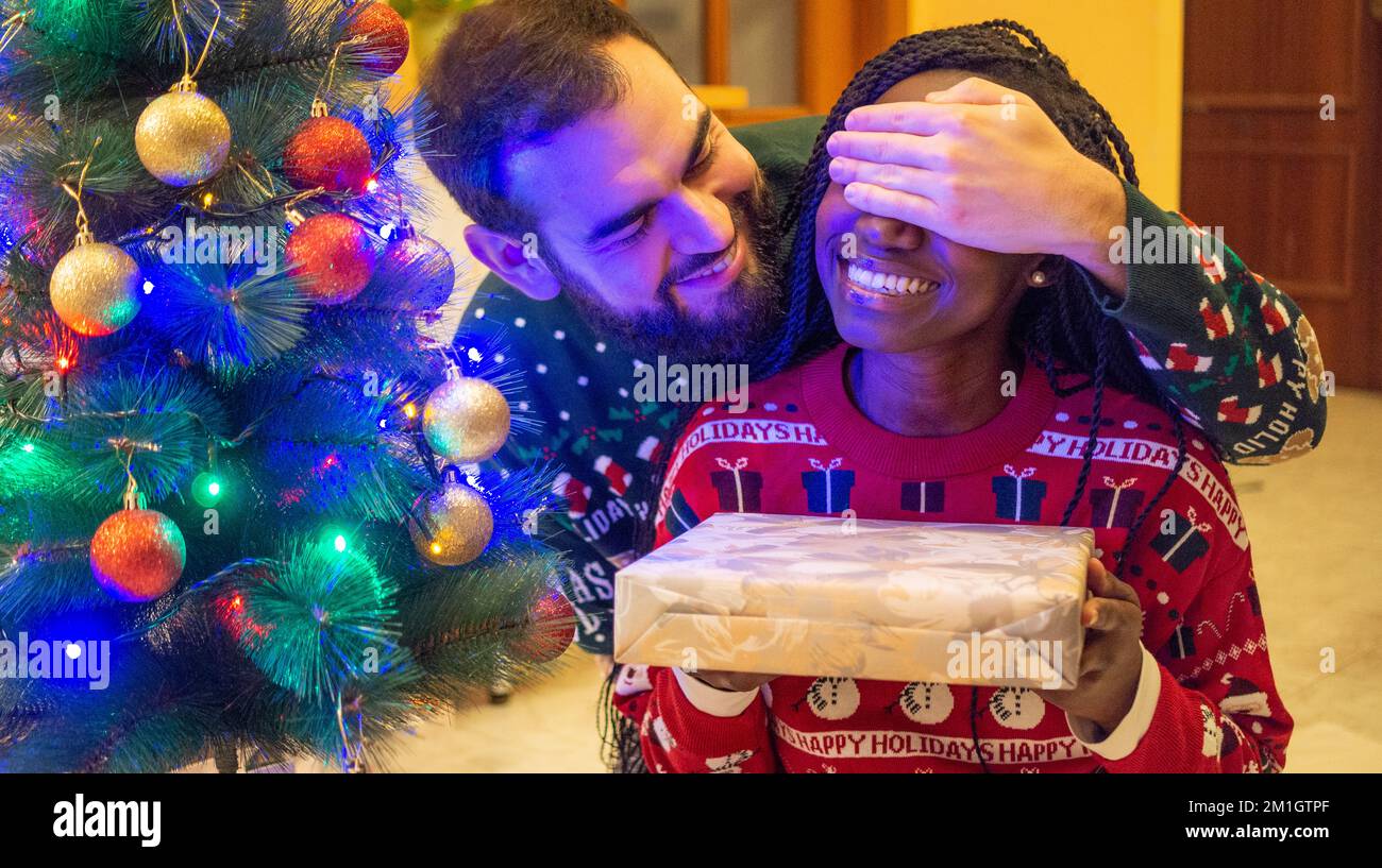 Happy man covering eyes of young african woman with his hands happy ...