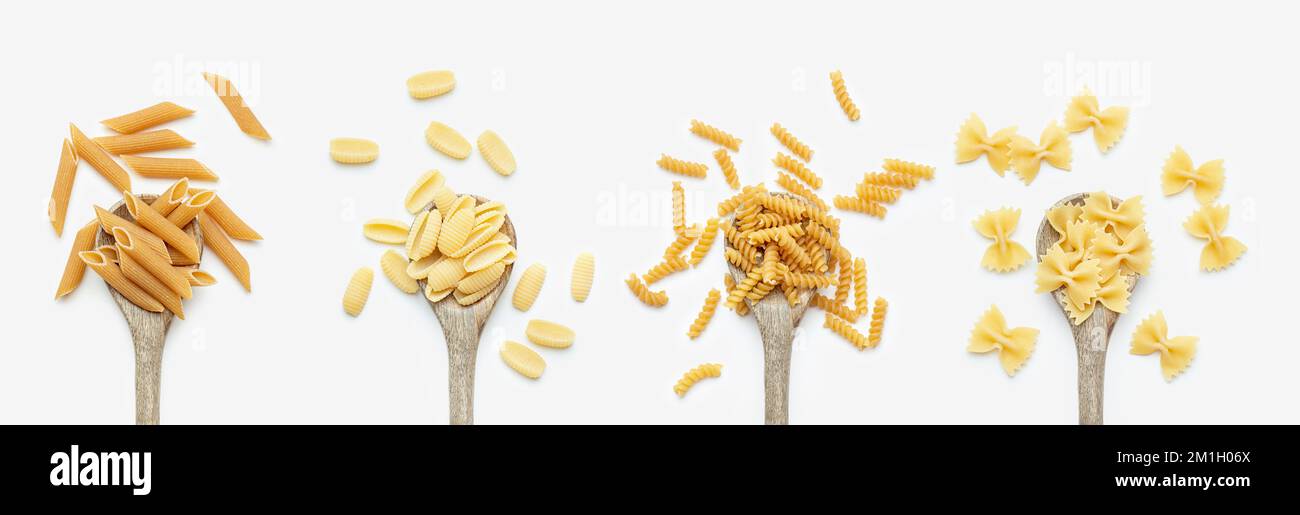 Different types of uncooked whole grain flour pasta in wooden spoons on ...