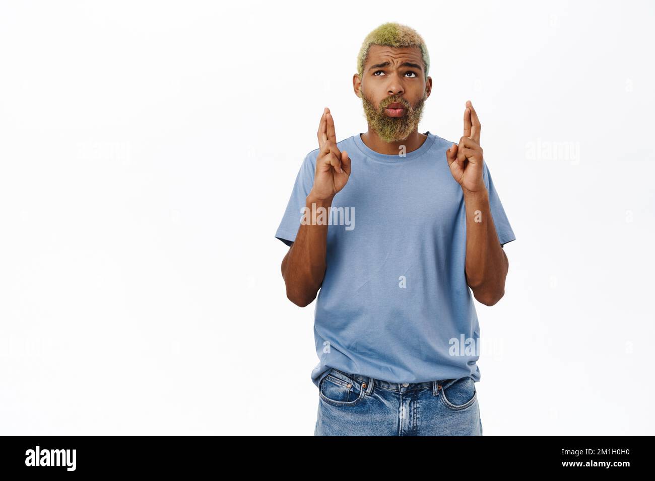 Hipster guy with yellow beard makes wish, holds fingers cross, praying ...
