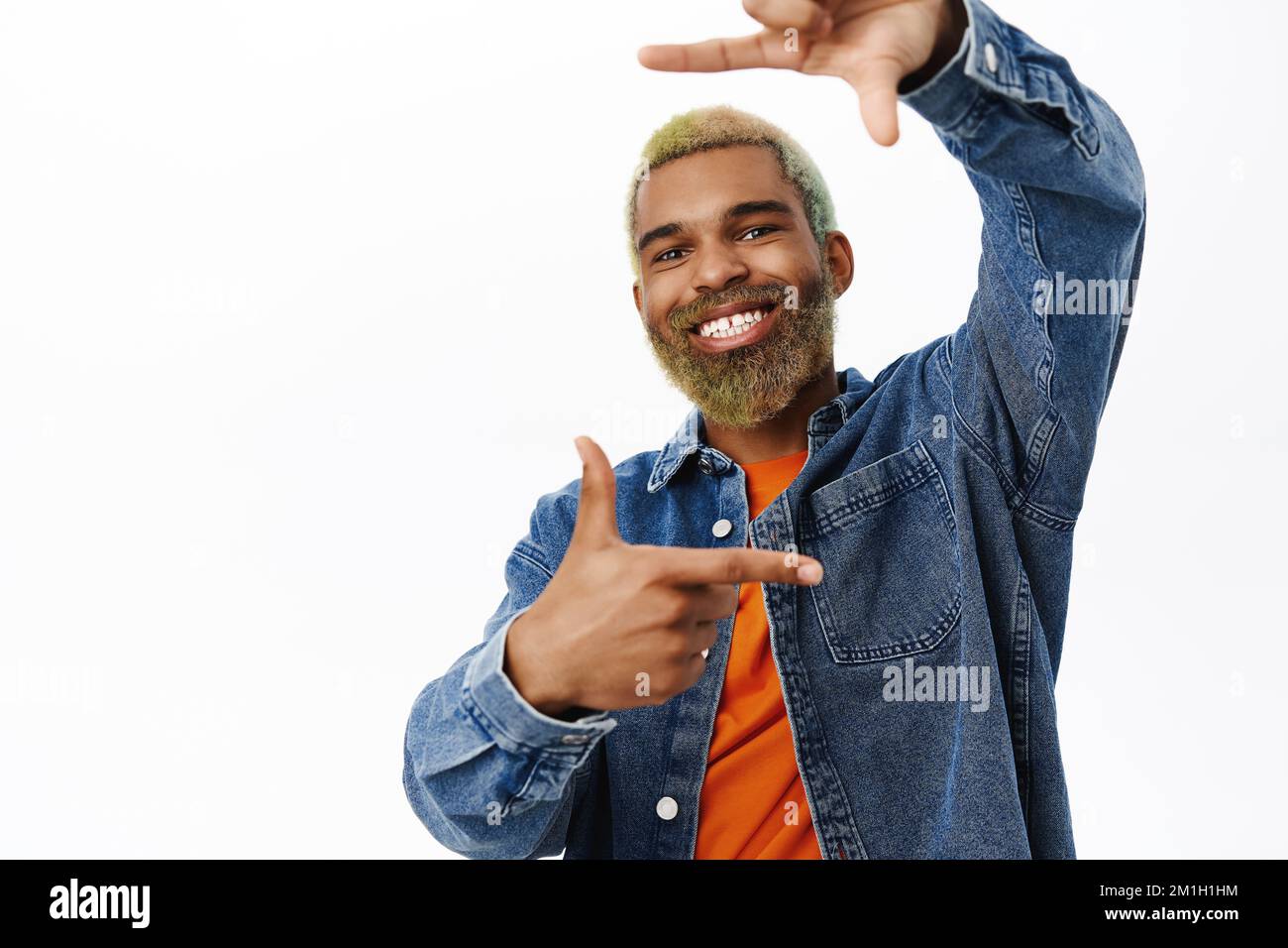 Snap. Stylish young man takes picture of you, looks through finger ...