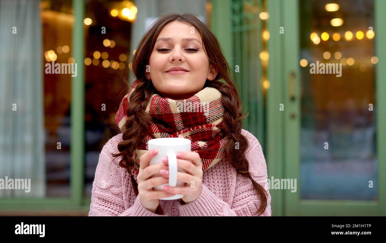 woman in checkered scarf drink hot coffee with marshmallow on street ...