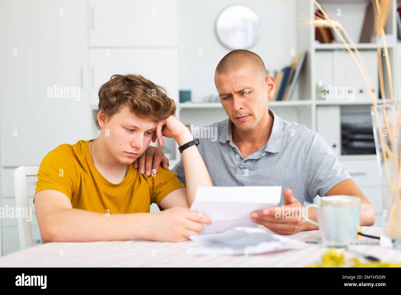 Depressed father and son reading letter Stock Photo - Alamy