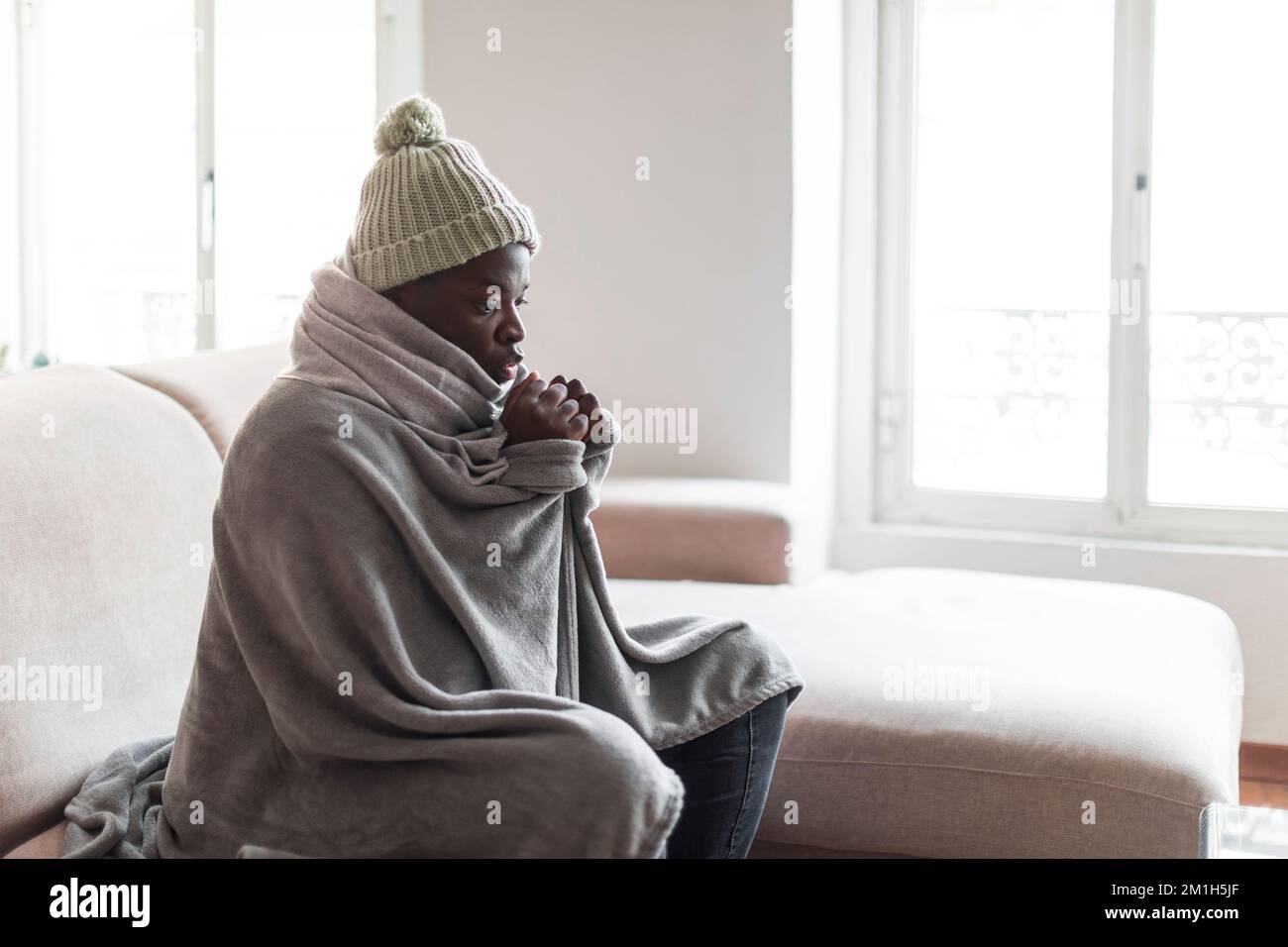 Unwell stressed man in hat, blanket sit in cold apartment Stock Photo ...