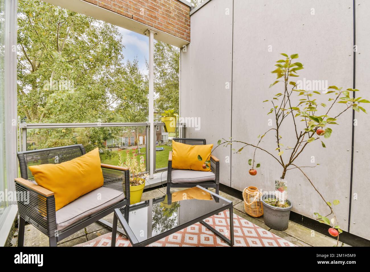 a patio with two chairs and an apple tree in the back, on top of a ...