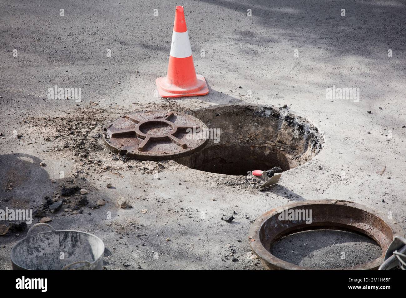 uncovered manhole on asphalt with signaling icons Stock Photo - Alamy