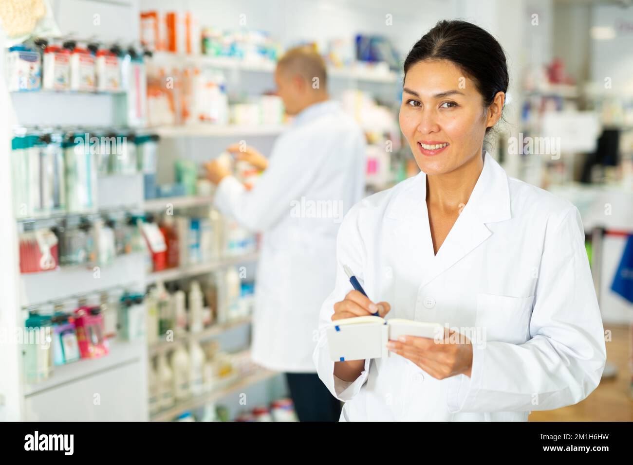 Positive female pharmacist writes in a notebook in the trading floor of ...