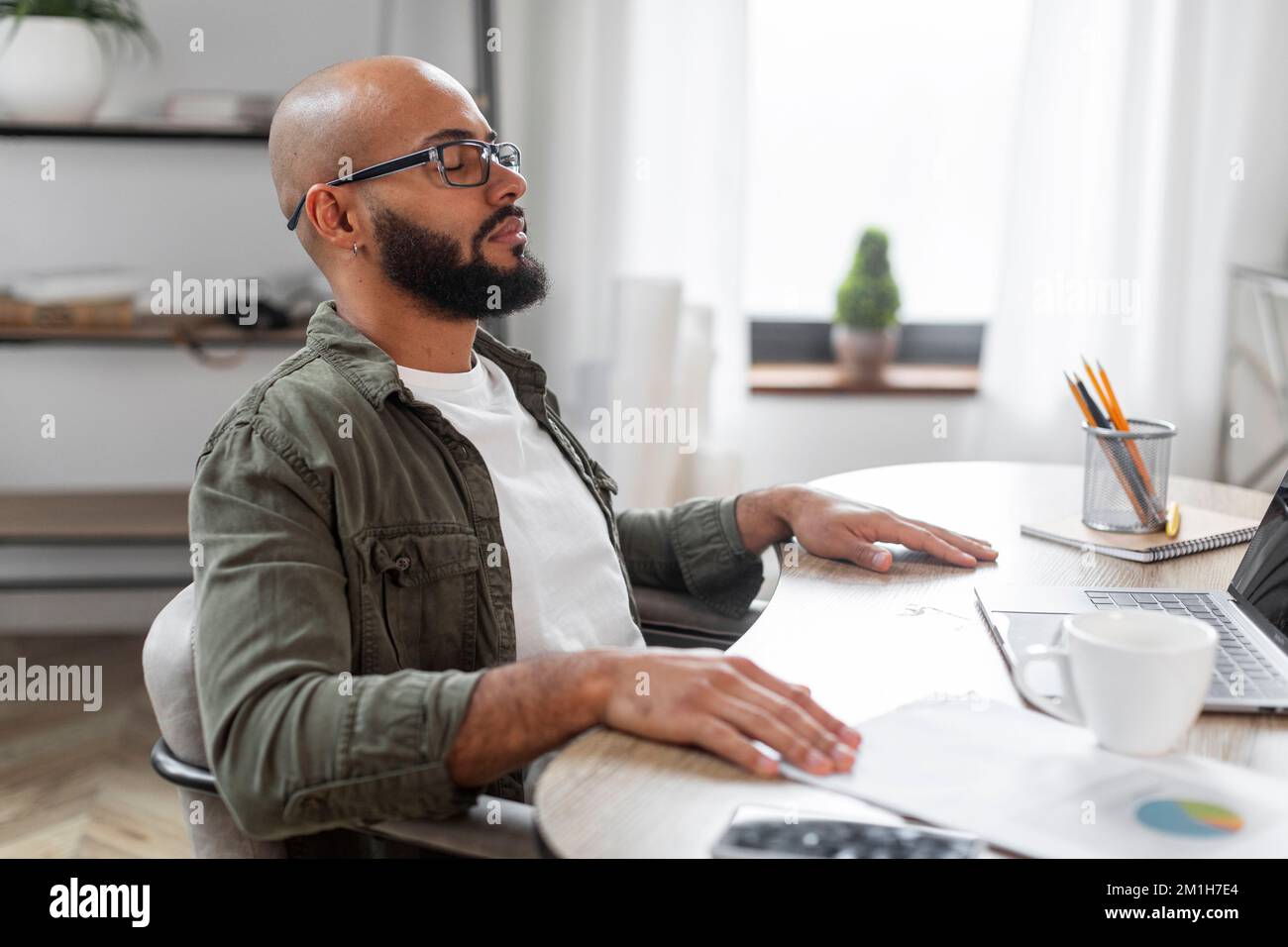 Tired latin male entrepreneur sitting in front of laptop with closed ...
