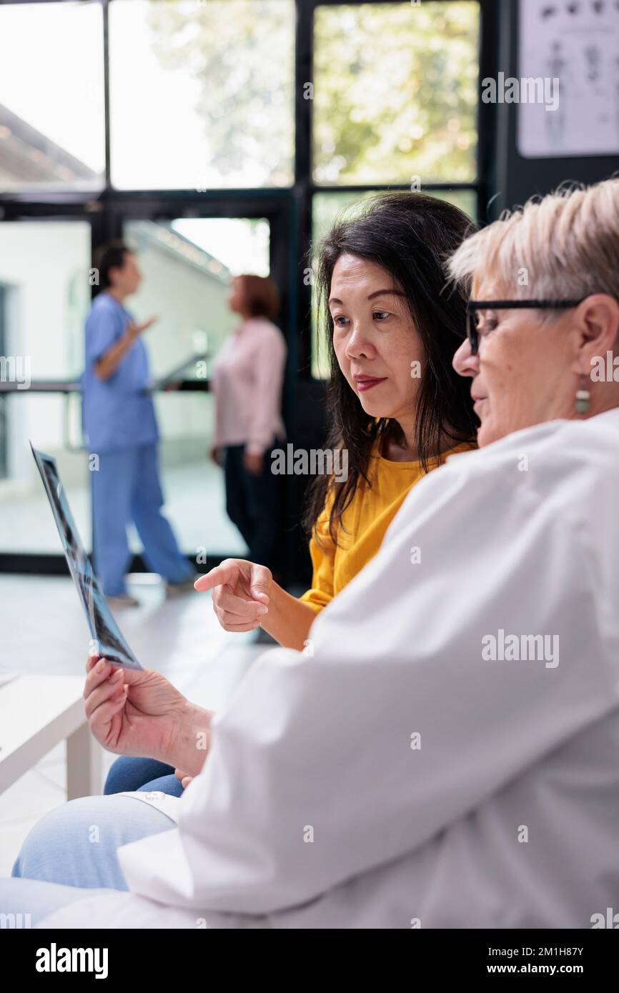 Senior physician doctor looking at radiography exam scan with asian ...
