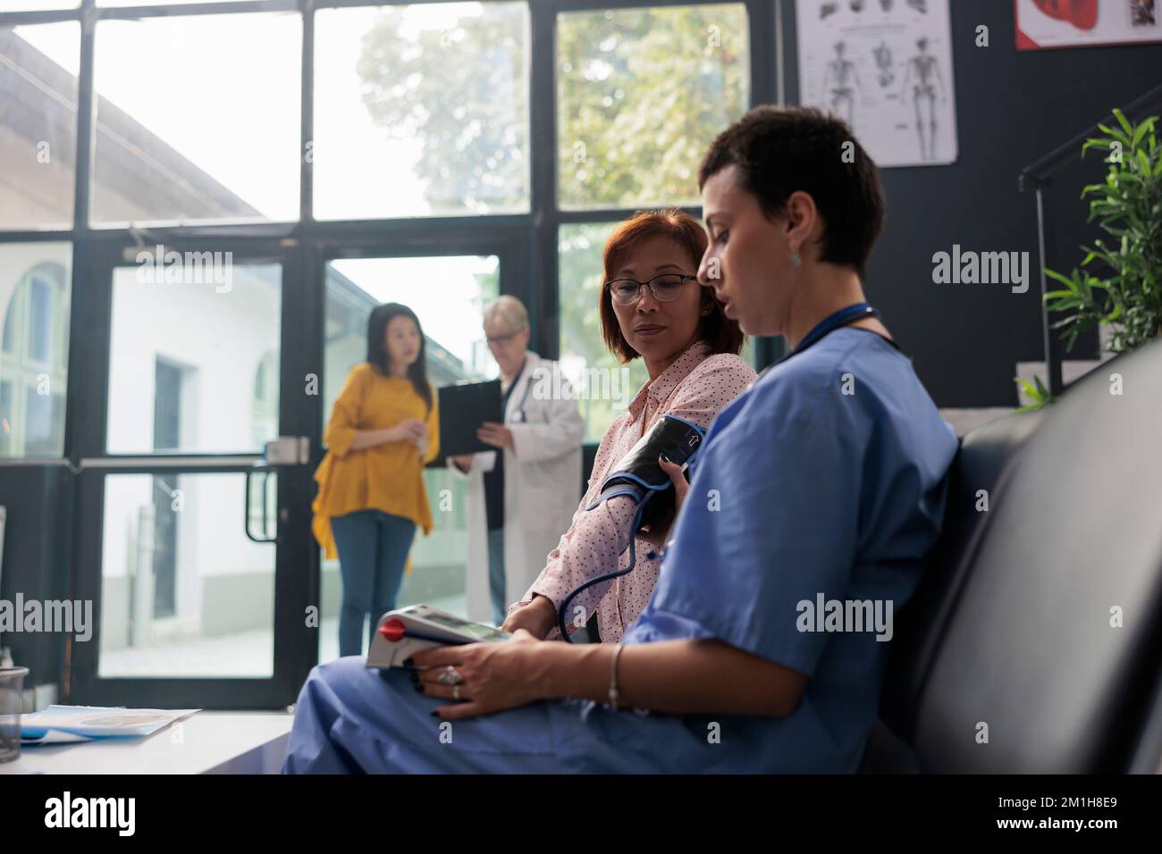 Medical assistant checking hypertension on tonometer in waiting area at ...