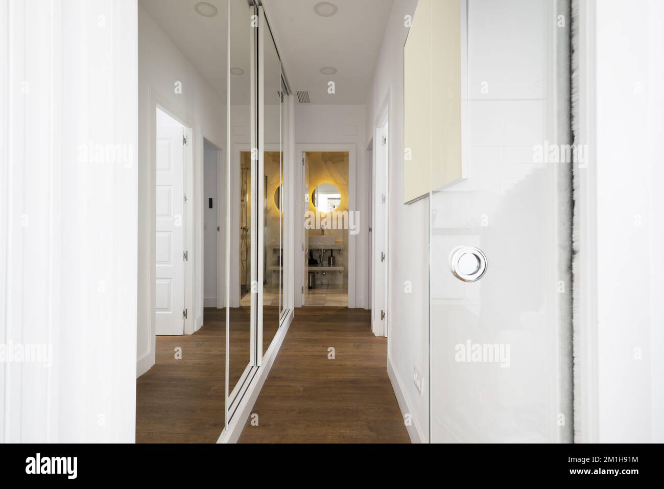 A long corridor in a house with white materials on the walls, wooden ...