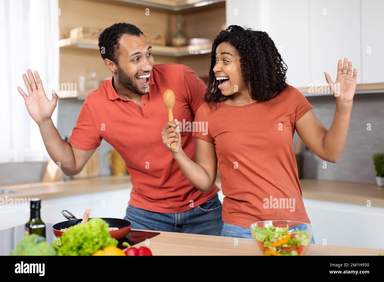 Glad Young Black Man And Woman In Red T Shirts Have Fun Singing At