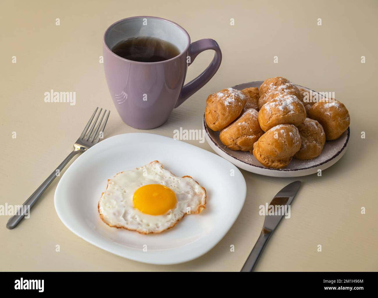 Breakfast with fried eggs, a cup of tea and profiteroles Stock Photo ...