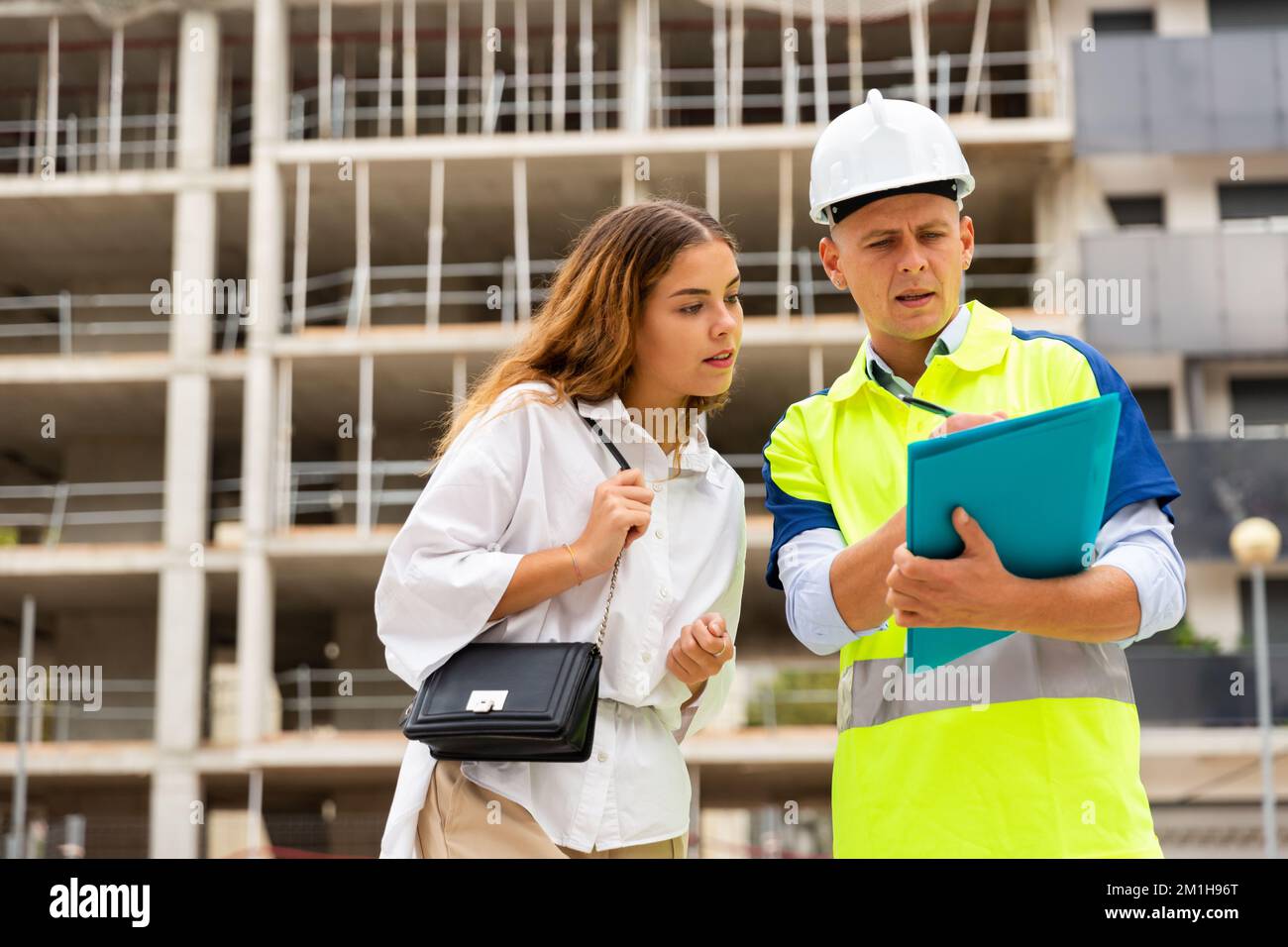 Builder talking with client at construction site Stock Photo - Alamy