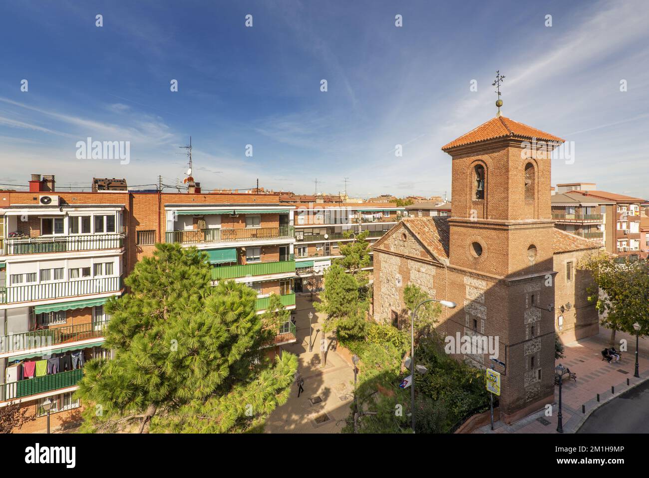 A neighborhood church with a clay brick bell tower between the ...