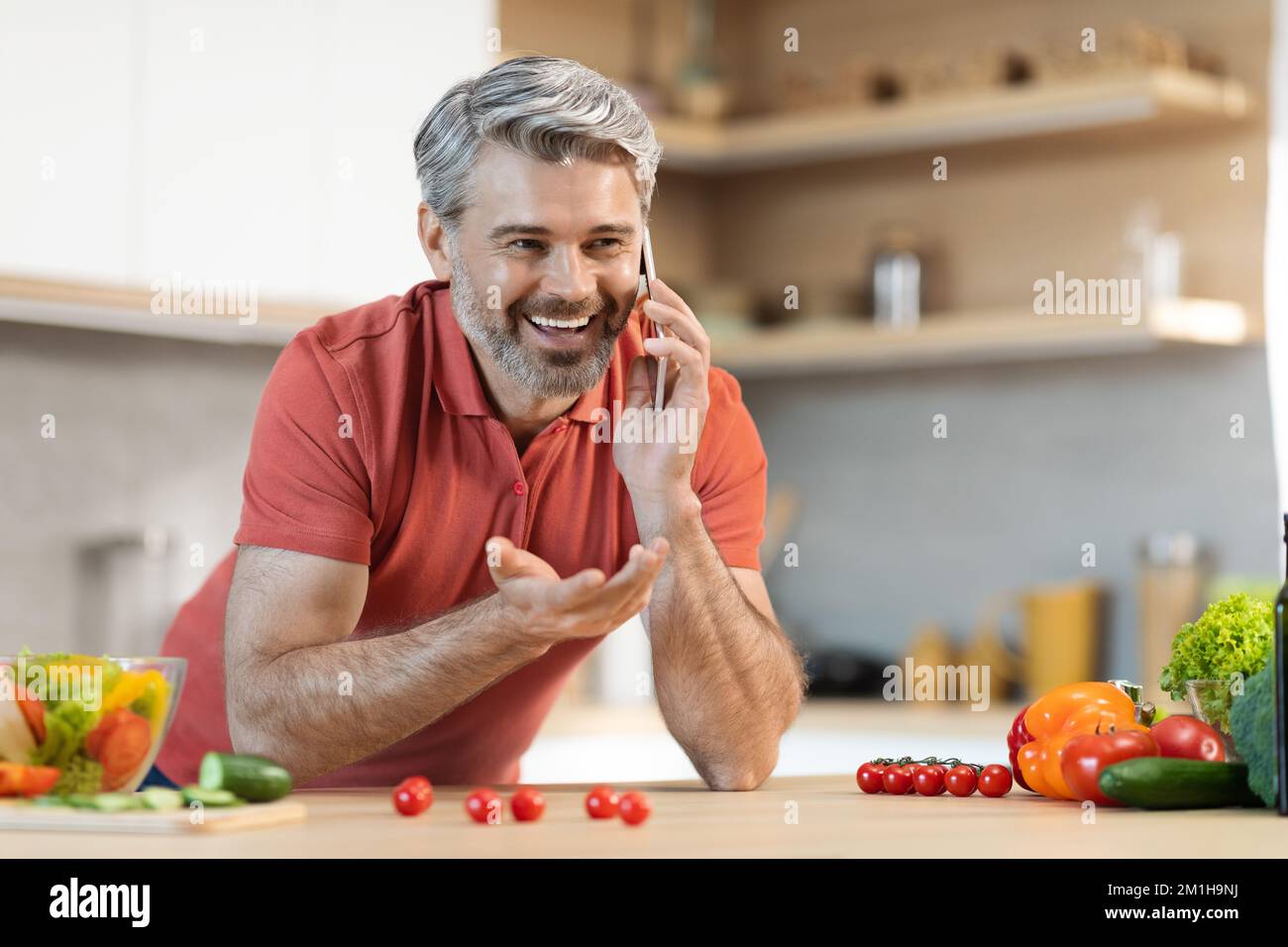 Happy middle aged man having phone conversation while cooking Stock ...