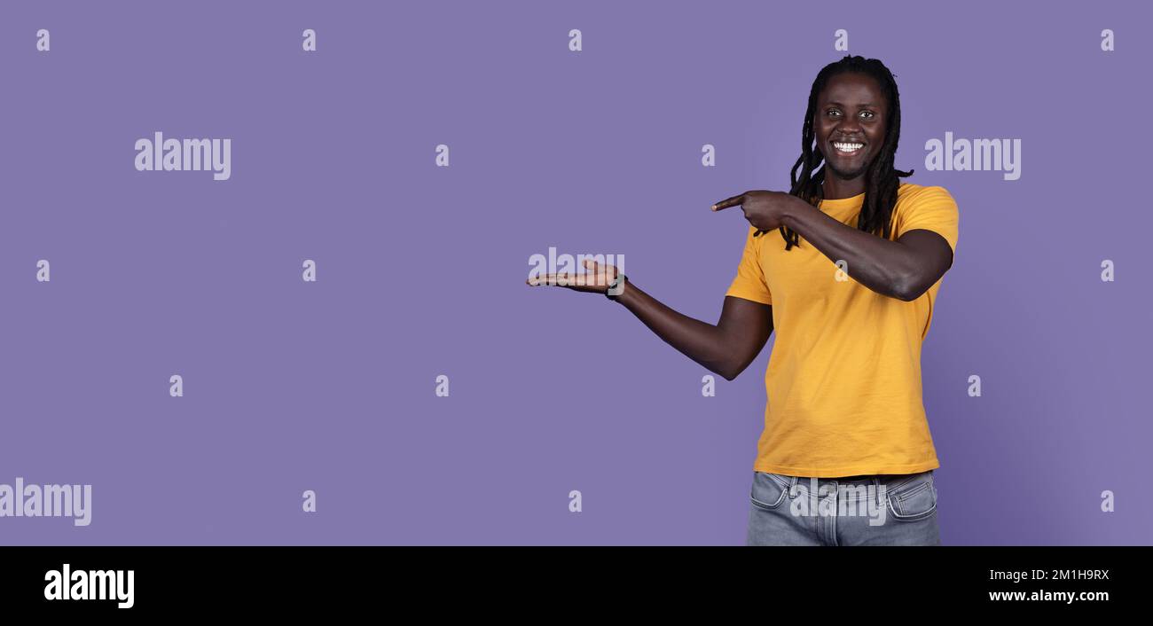 Positive african american guy holding something invisible on his hand ...