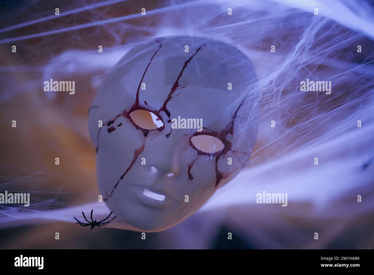 Color image of a white mask, painted with blood, in some spiderwebs and ...