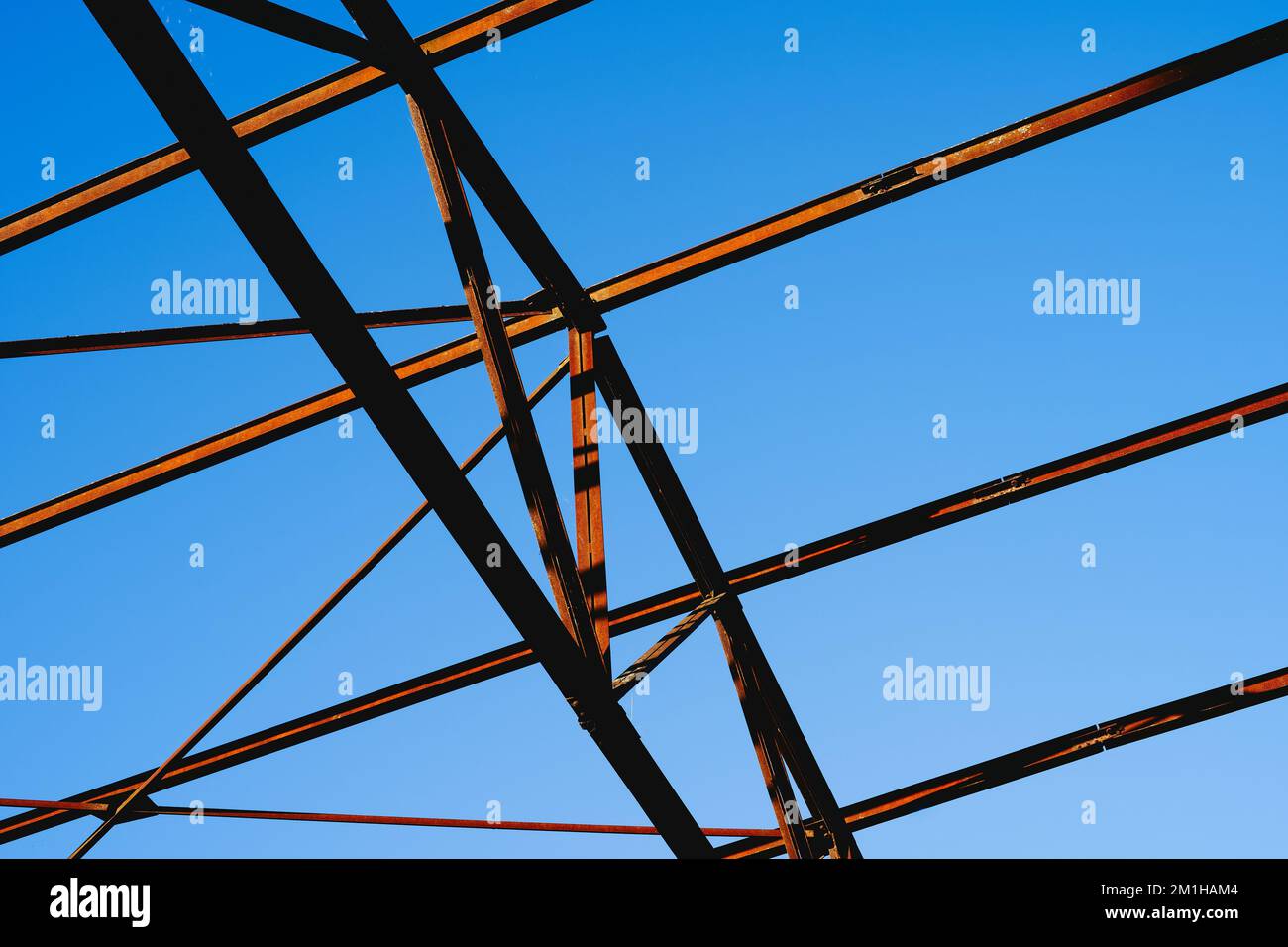 A low-angle shot of the steel truss and purlin of a building under a ...