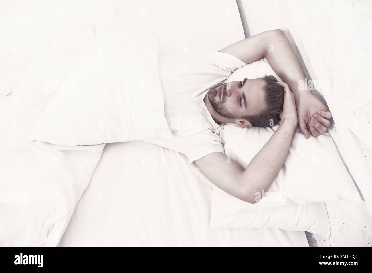 Tips promoting healthful sleep habits. Handsome man relaxing in bed ...