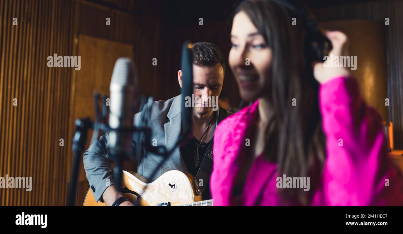 medium closeup view of a singer girl and a guitarist behind her on ...