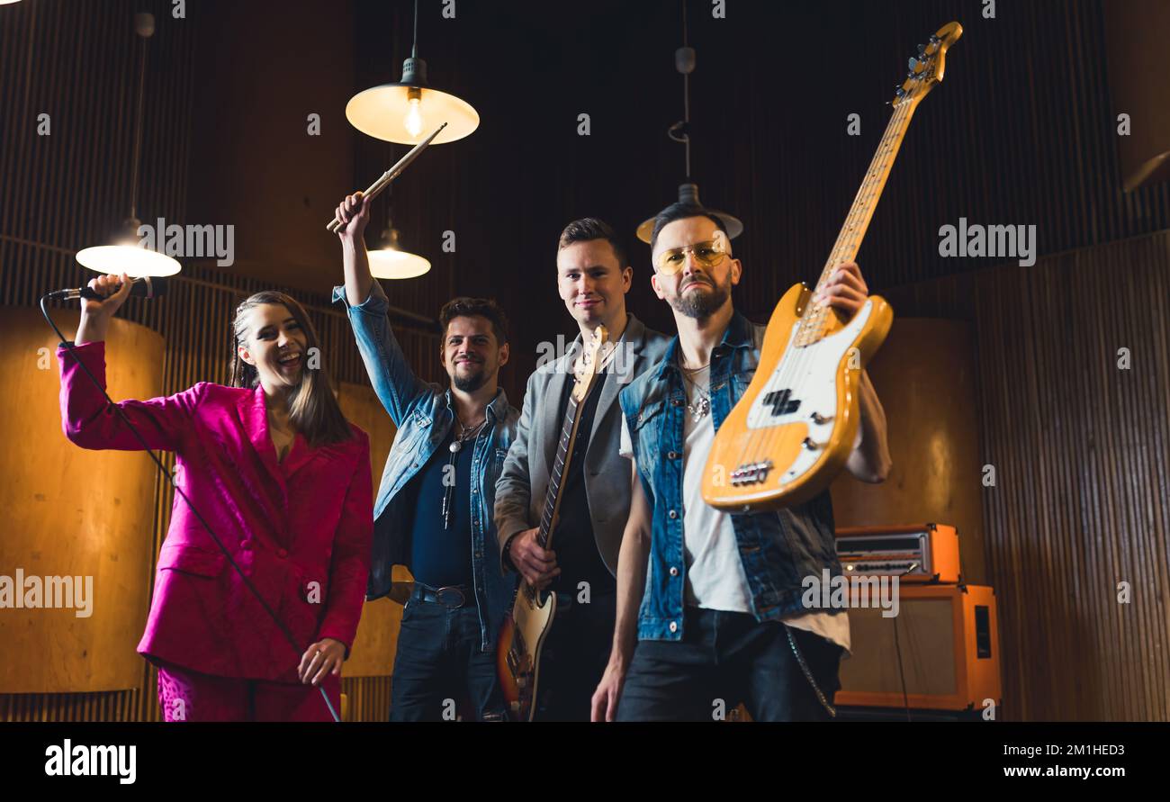 medium shot of a music band standing happy in the recording studio ...