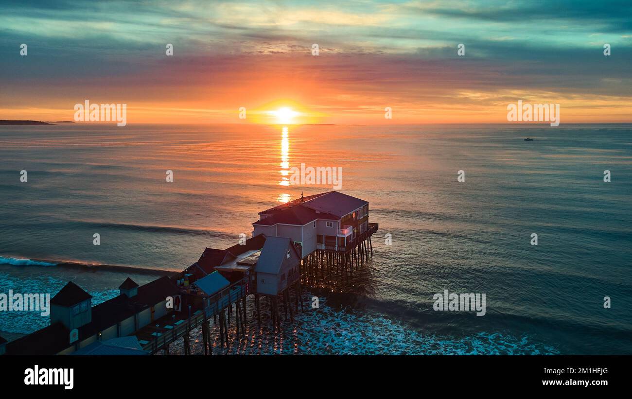 Pier with shops on Maine ocean during stunning sunrise light from ...