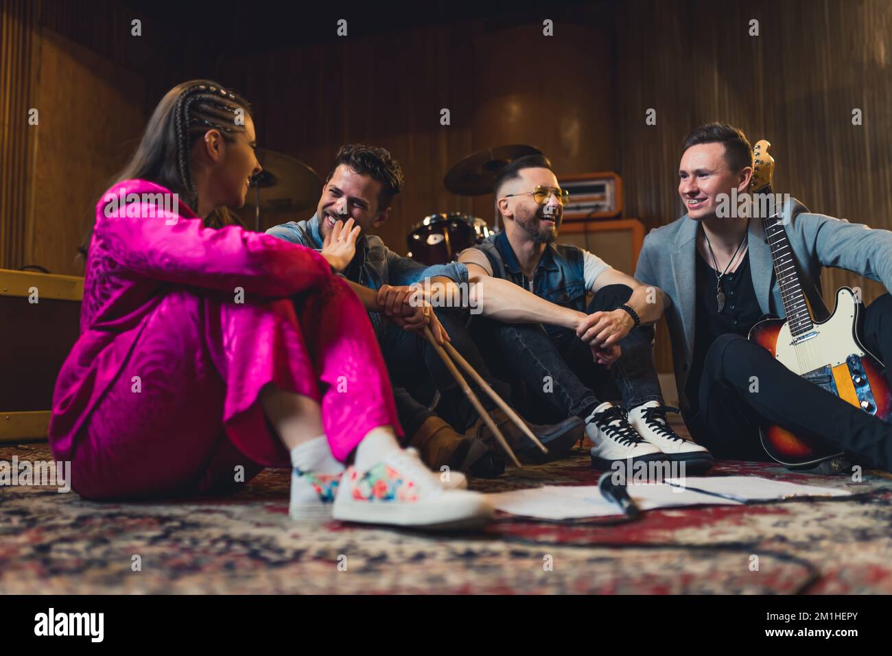 Music is fun. Band members laughing while sitting on a carpet. Four ...