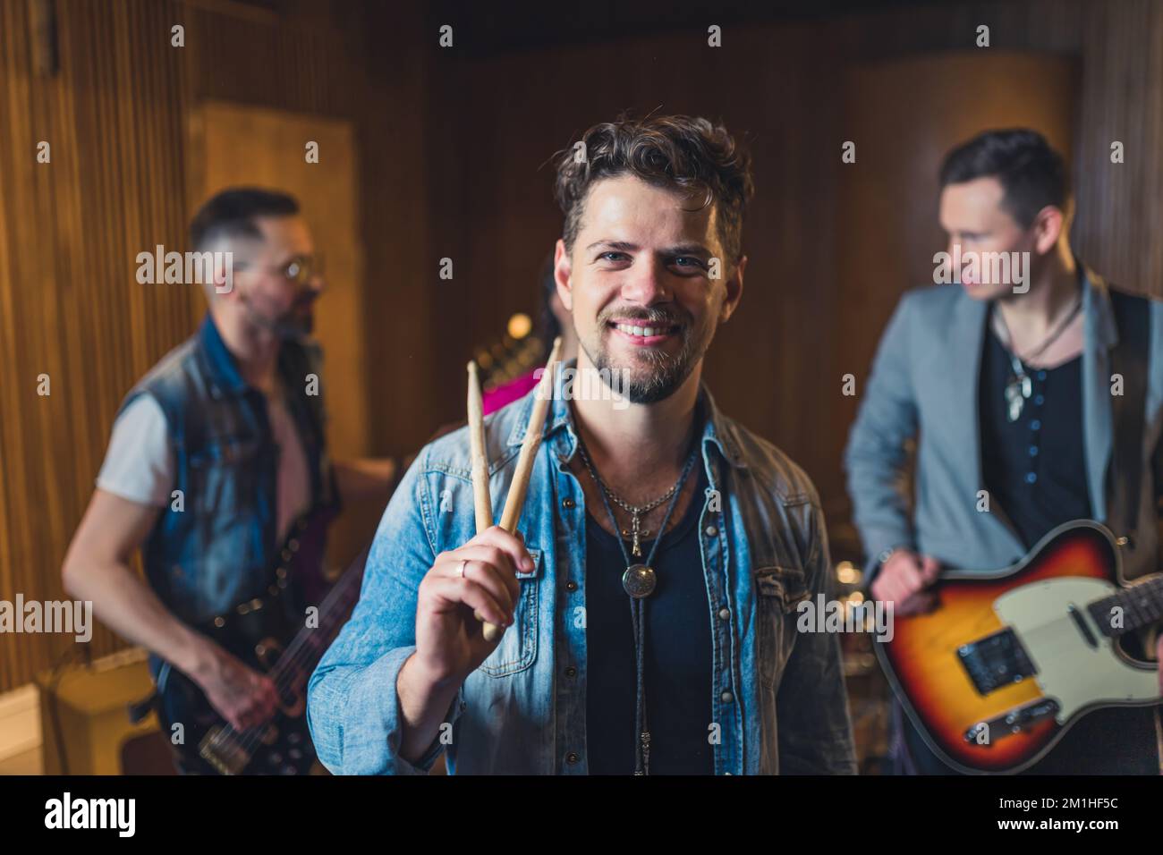 music band on repetition, drummer standing in front and holding sticks ...