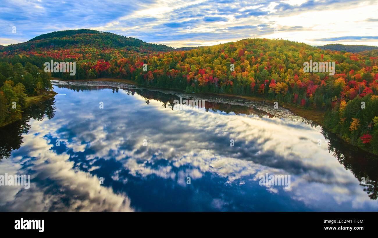 Mountains in peak fall surround reflective lake in early morning light ...