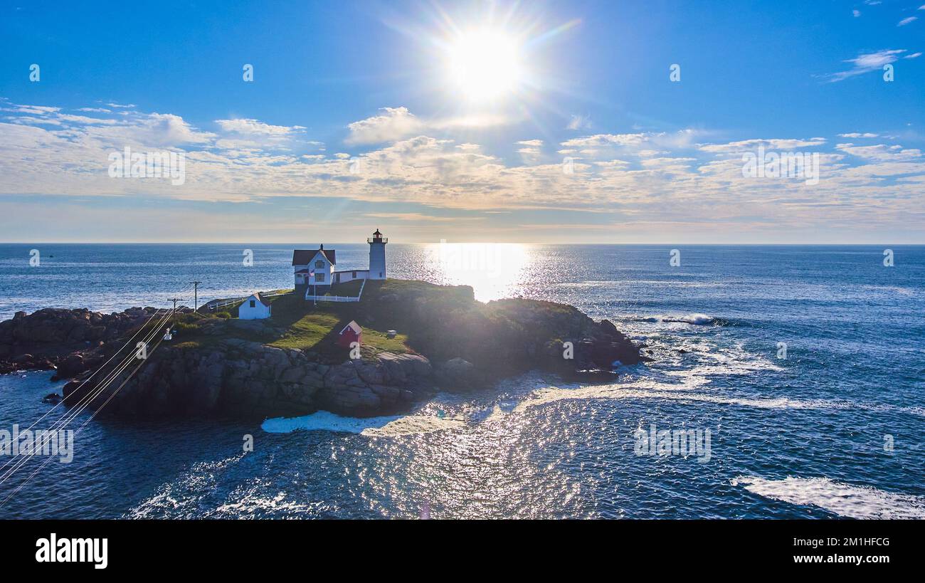 Small Maine island with lighthouse from above with sun shining over ...