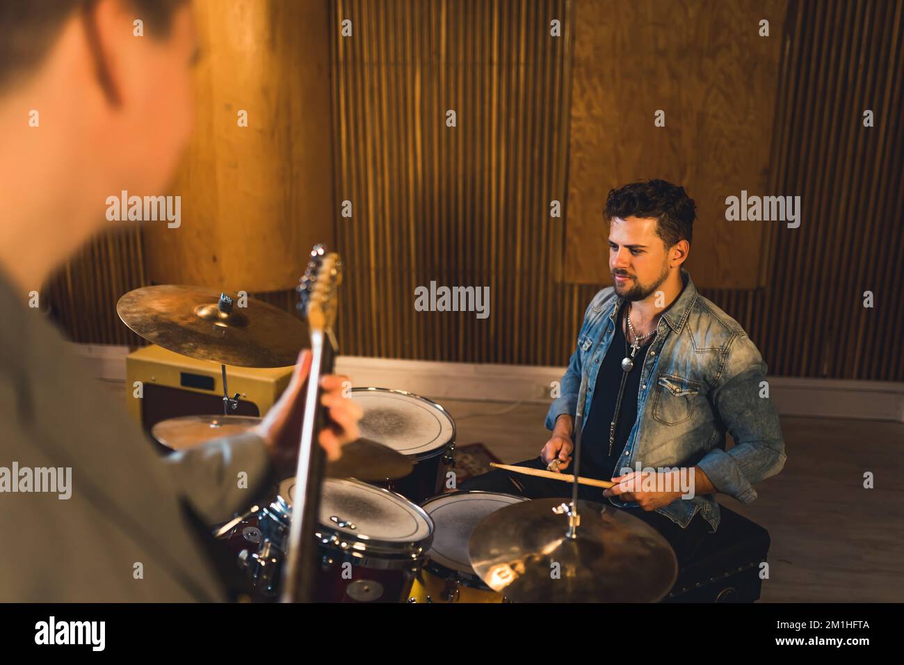 young drummer with black curly hair sitting and playing drums with his ...
