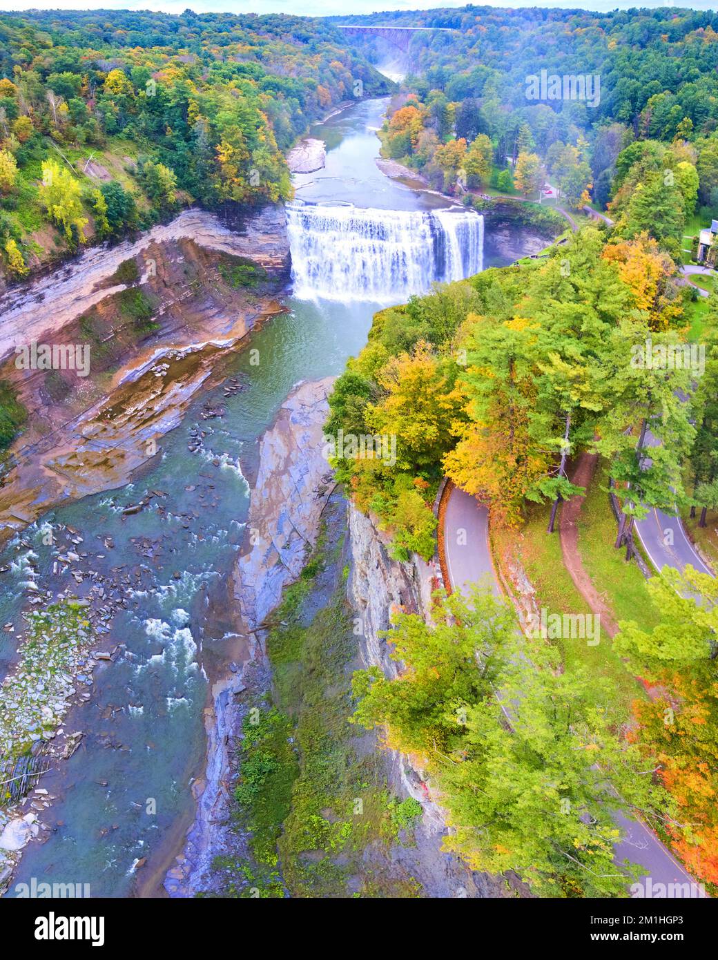 Aerial panorama over road along edge of cliffs with raging waterfall ...