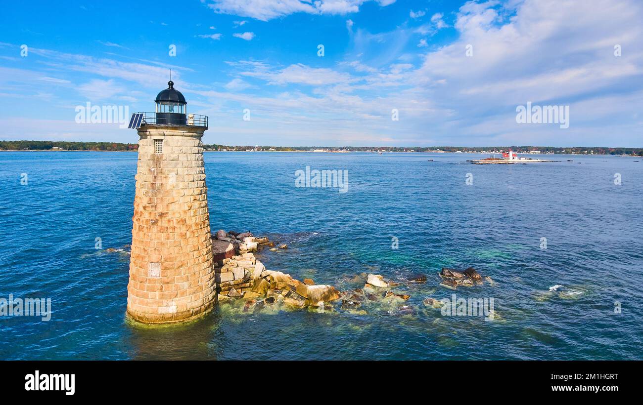 Lone stone tower lighthouse on broken rocks in Maine ocean Stock Photo ...